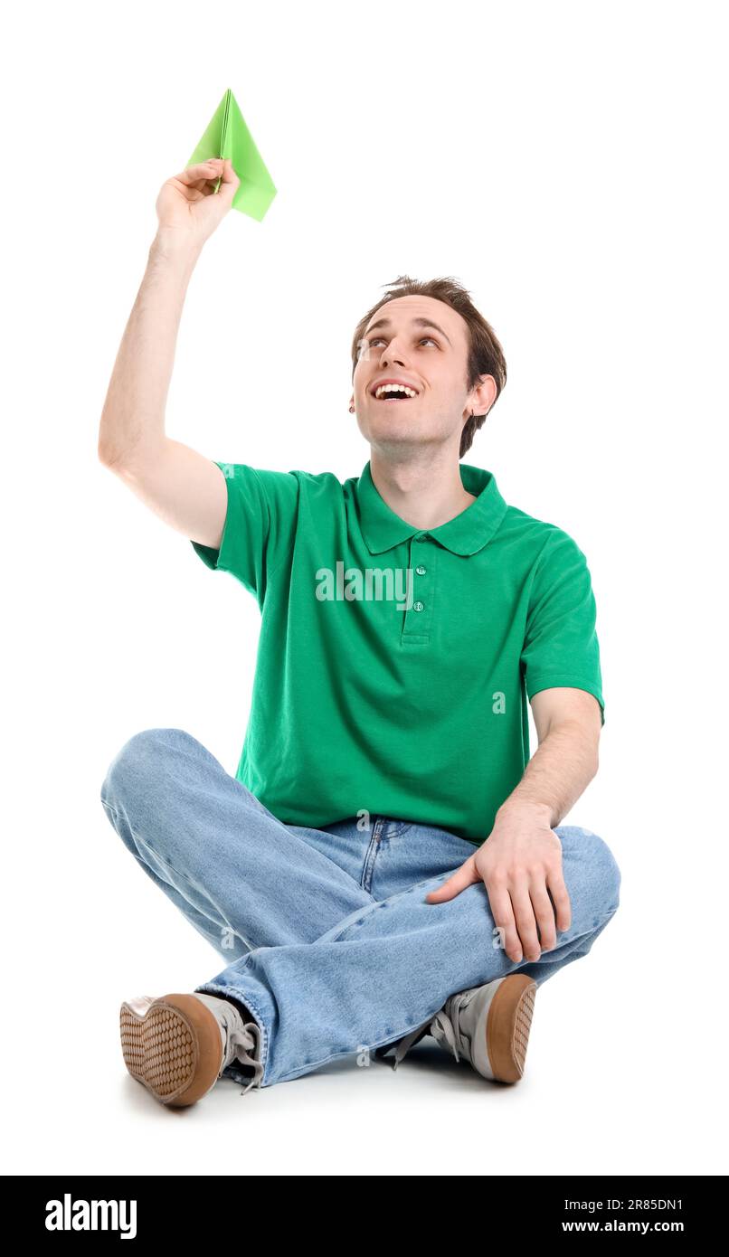 Young man with paper plane sitting on white background Stock Photo - Alamy