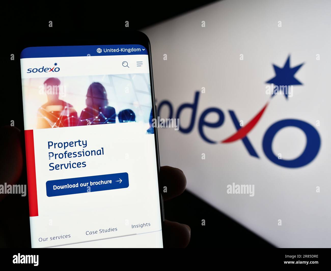 Person holding cellphone with web page of French facility management ...