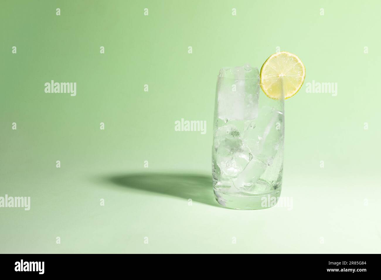 Cold glass full of ice with a lime, ready to serve light green with ...