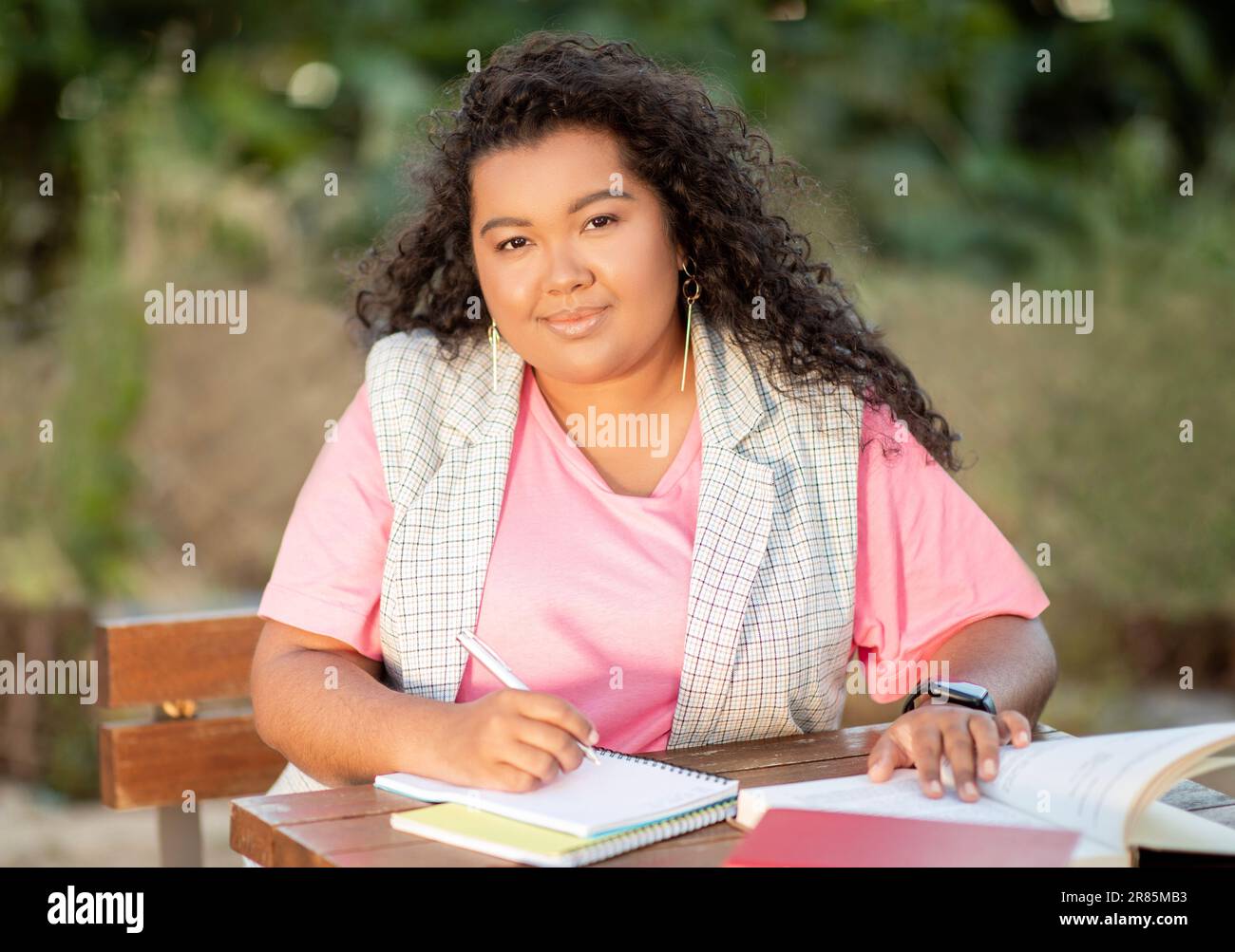 Latin student lady studying, taking notes in campus park Stock Photo ...