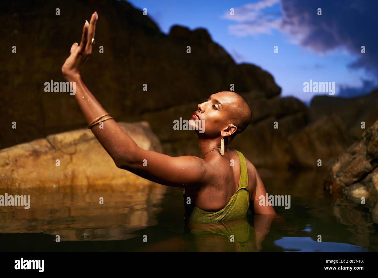 Gender fluid black person dives out from water in natural still water ...