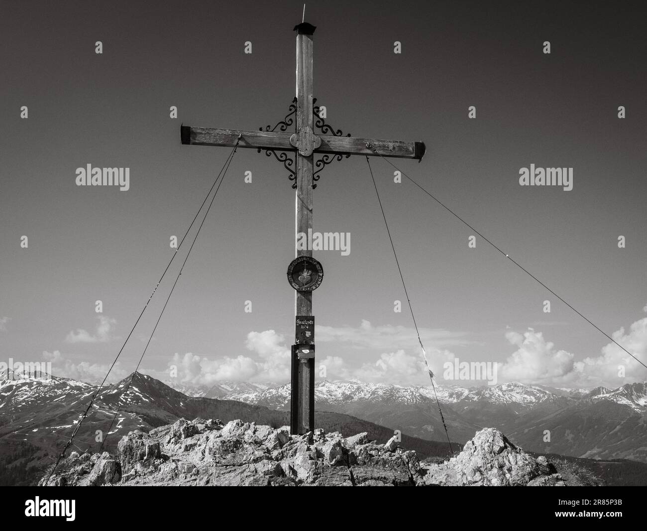 Summit cross with the alps in the background in a black and whtie theme ...
