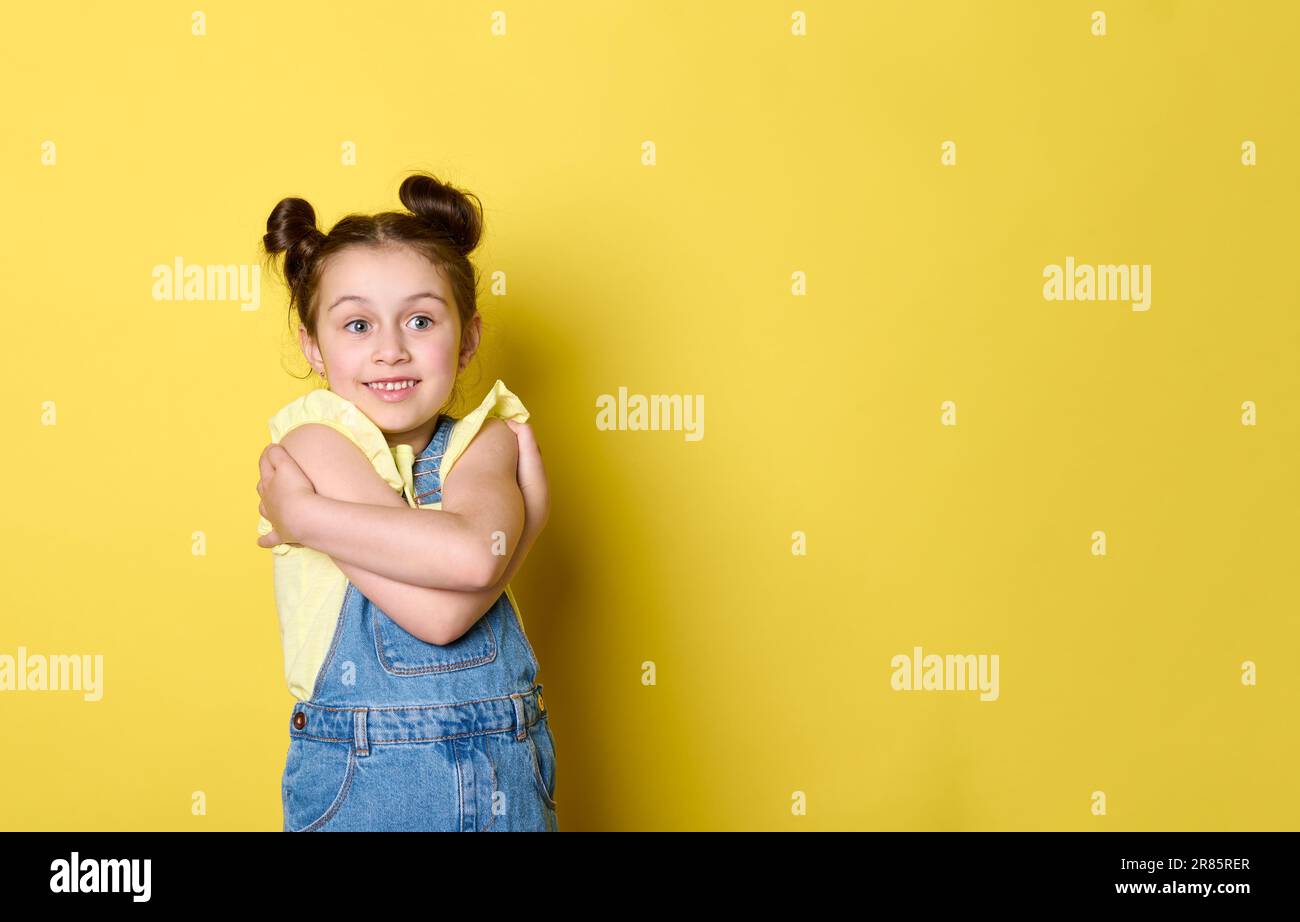Happy emotional child girl hugs herself, smiling, expressing positive ...