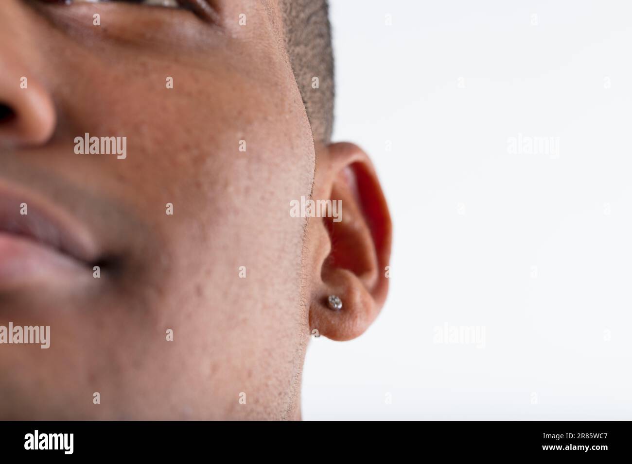 'In-focus detail of an earring on a young black man's ear. Barely ...
