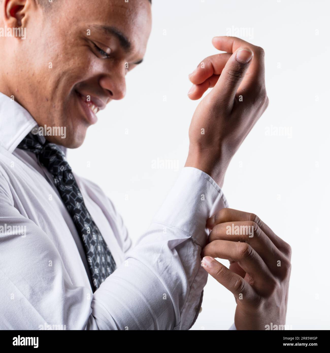 Sharp detail of a young black man's hands buttoning up an elegant white ...