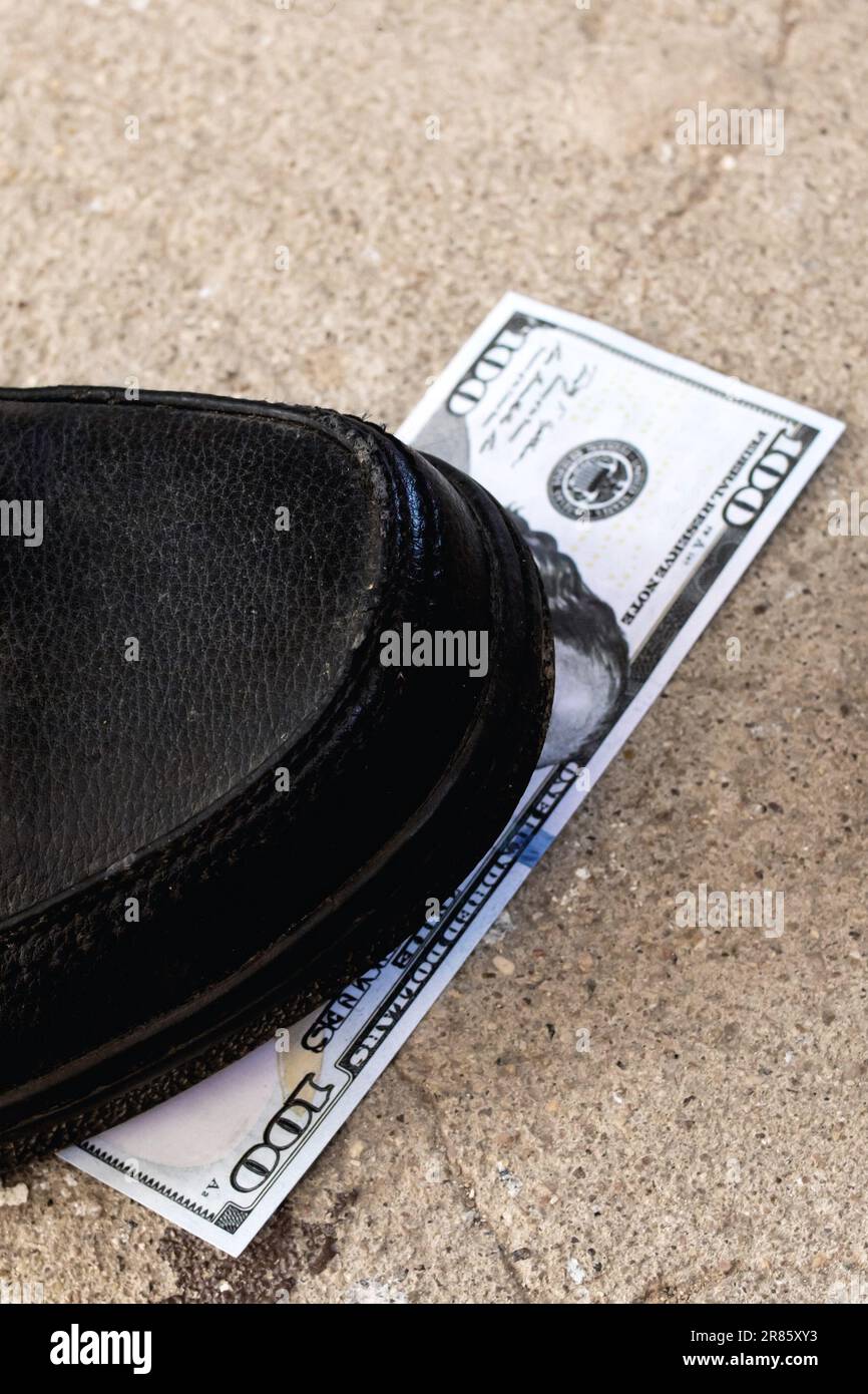 One hundred dollar bill under the shoe Stock Photo - Alamy