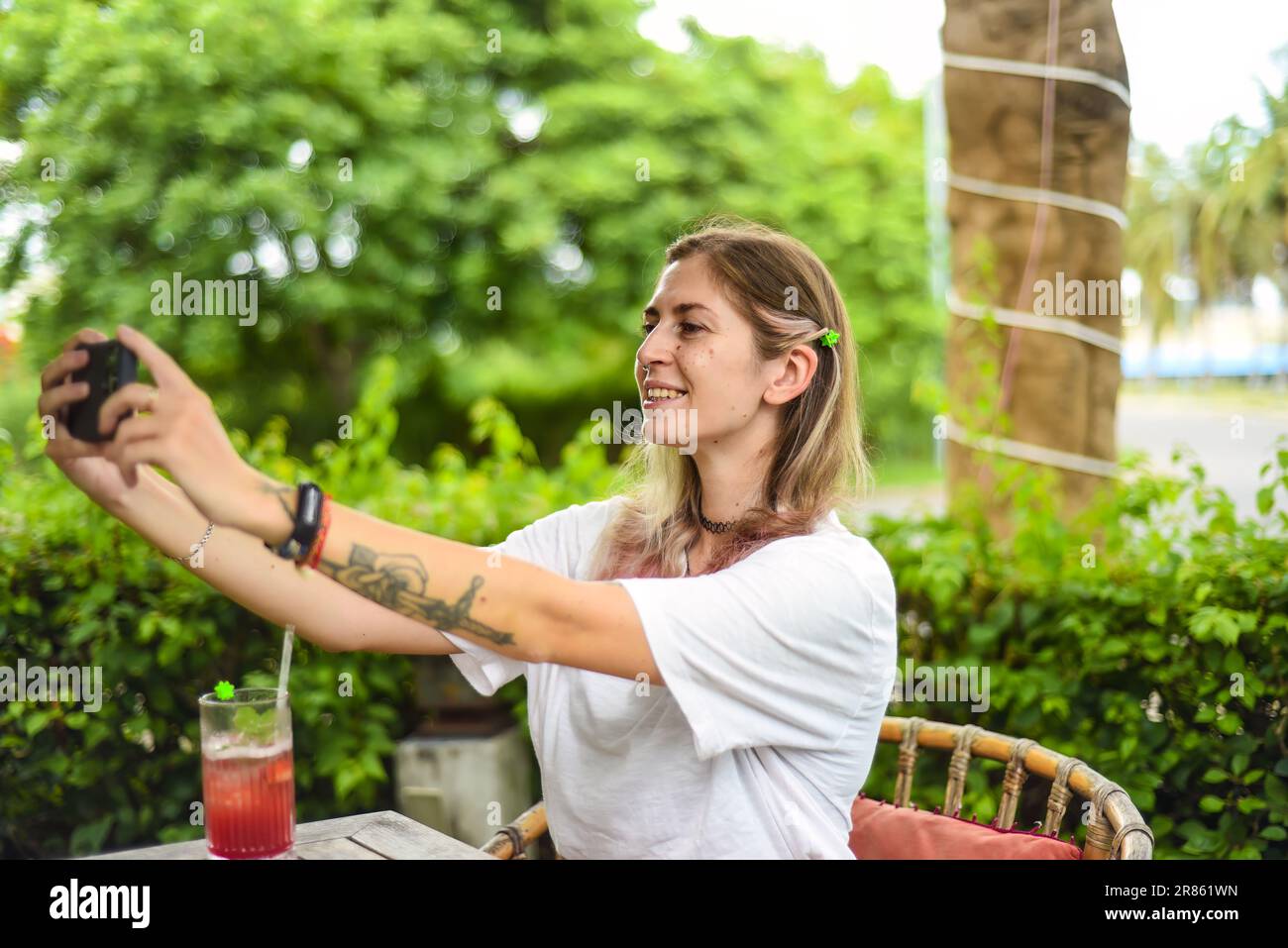 Cute woman taking a photo selfie and drinking tea in summer garden ...
