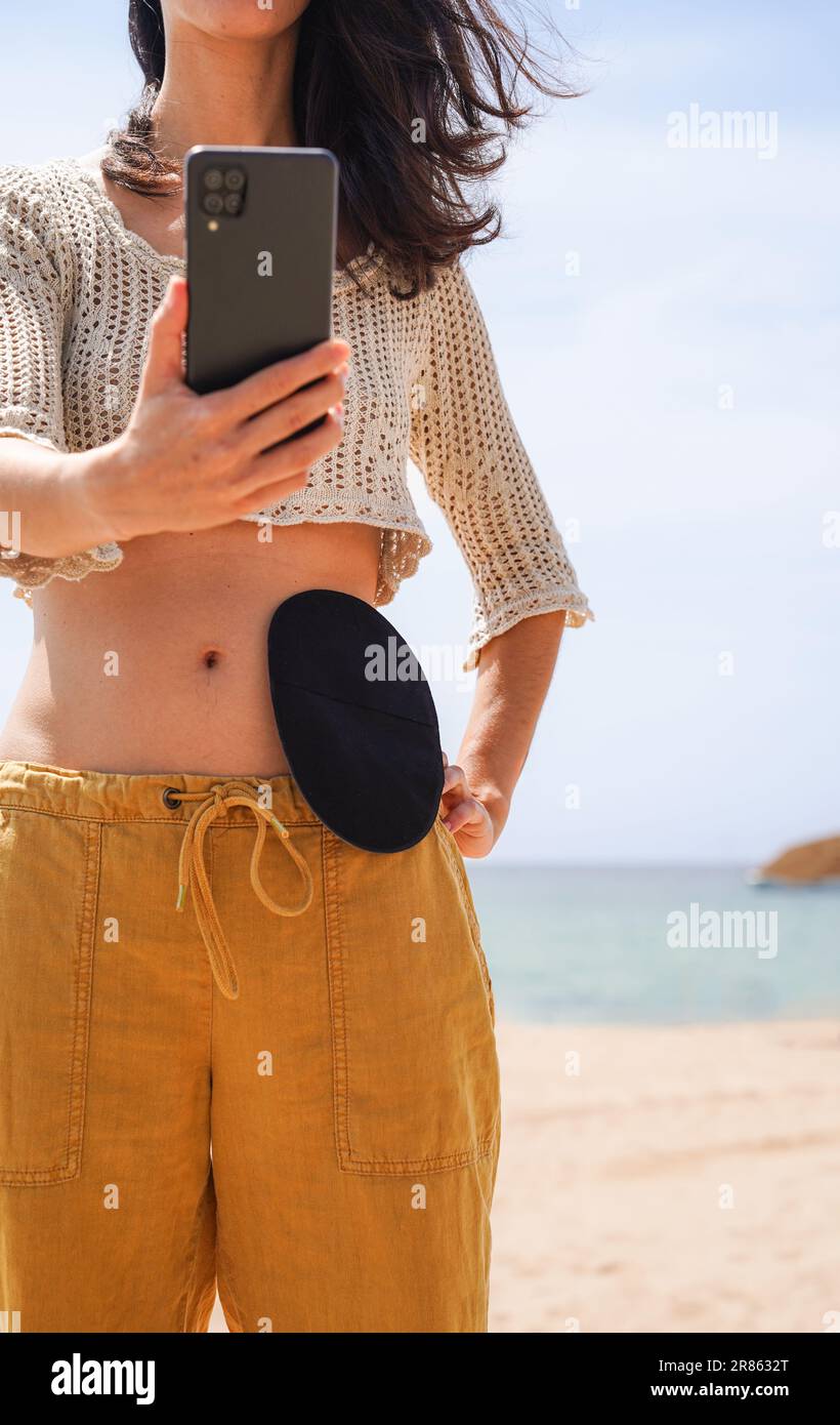 unrecognizable woman with a black ostomy bag taking a selfie in the ...