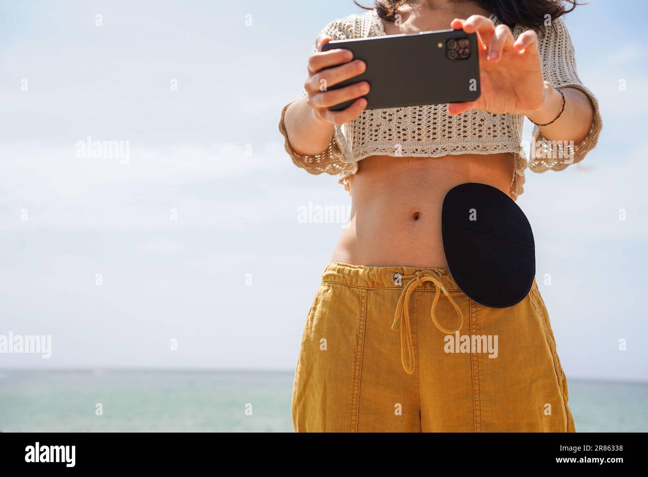 unrecognizable woman with a black ostomy bag taking a selfie in the ...