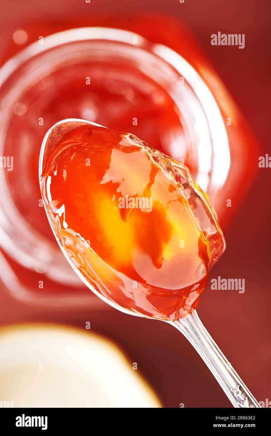 Quince-lemon jelly on teaspoon on background opened jar jelly Stock ...