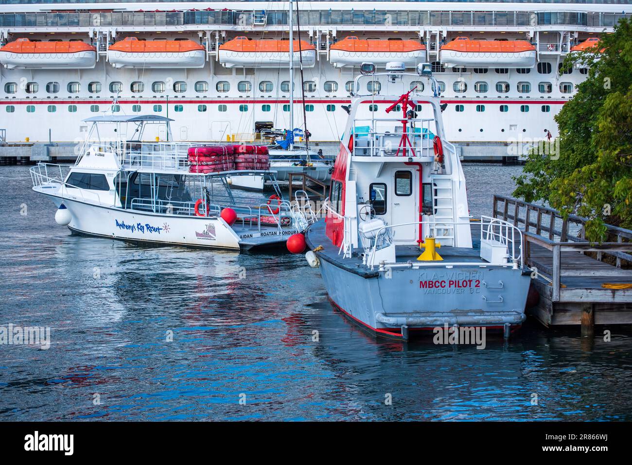 Small vessels docked in Roatan, Honduras, adjacent to Carnival Vista ...
