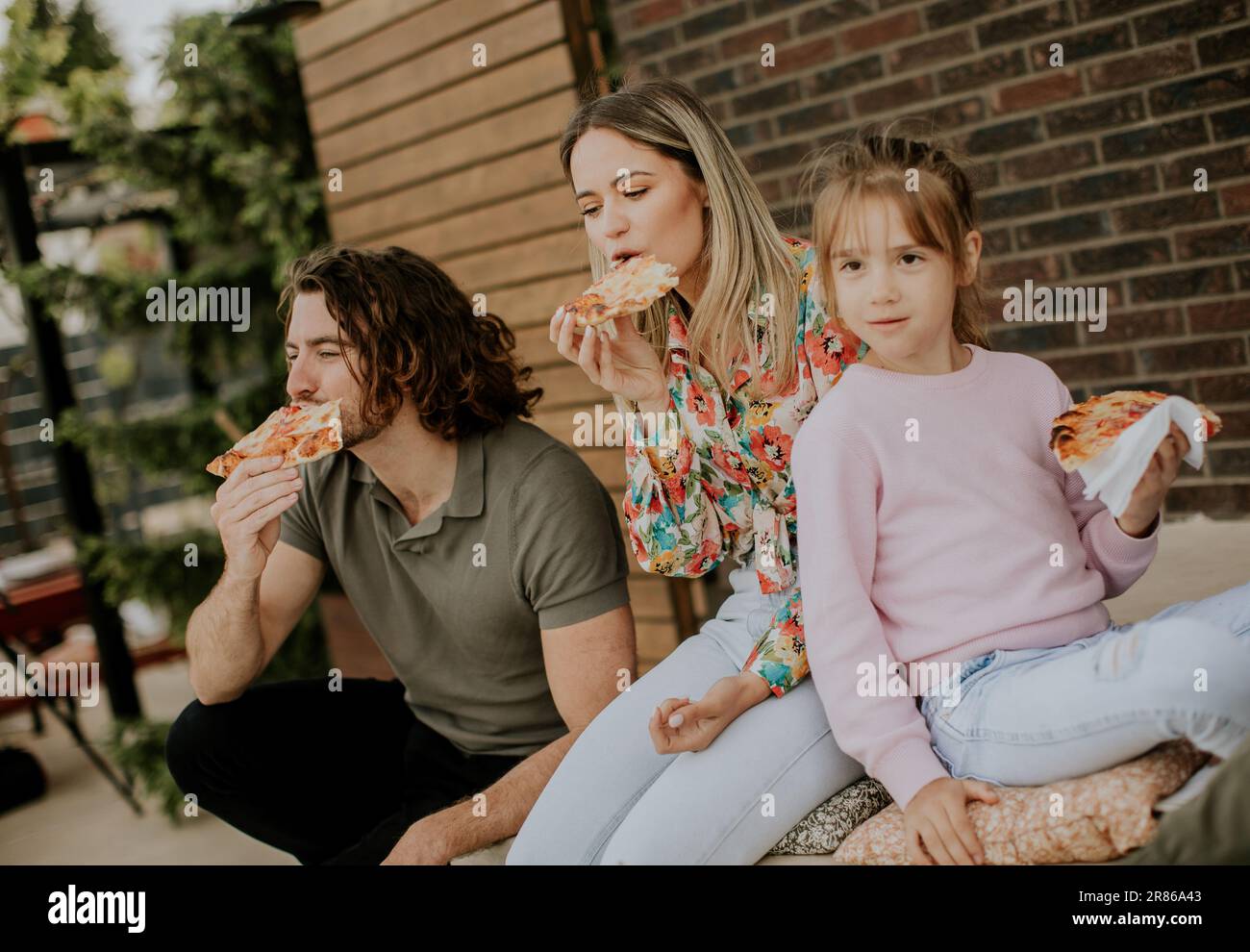 Happy young family eating pizza in the house backyard Stock Photo - Alamy