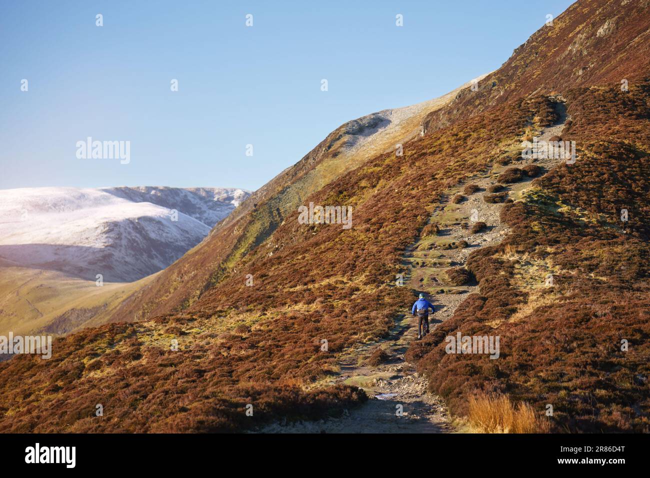 A mountain biker riding up the trail to the summit of Grisedale Pike ...