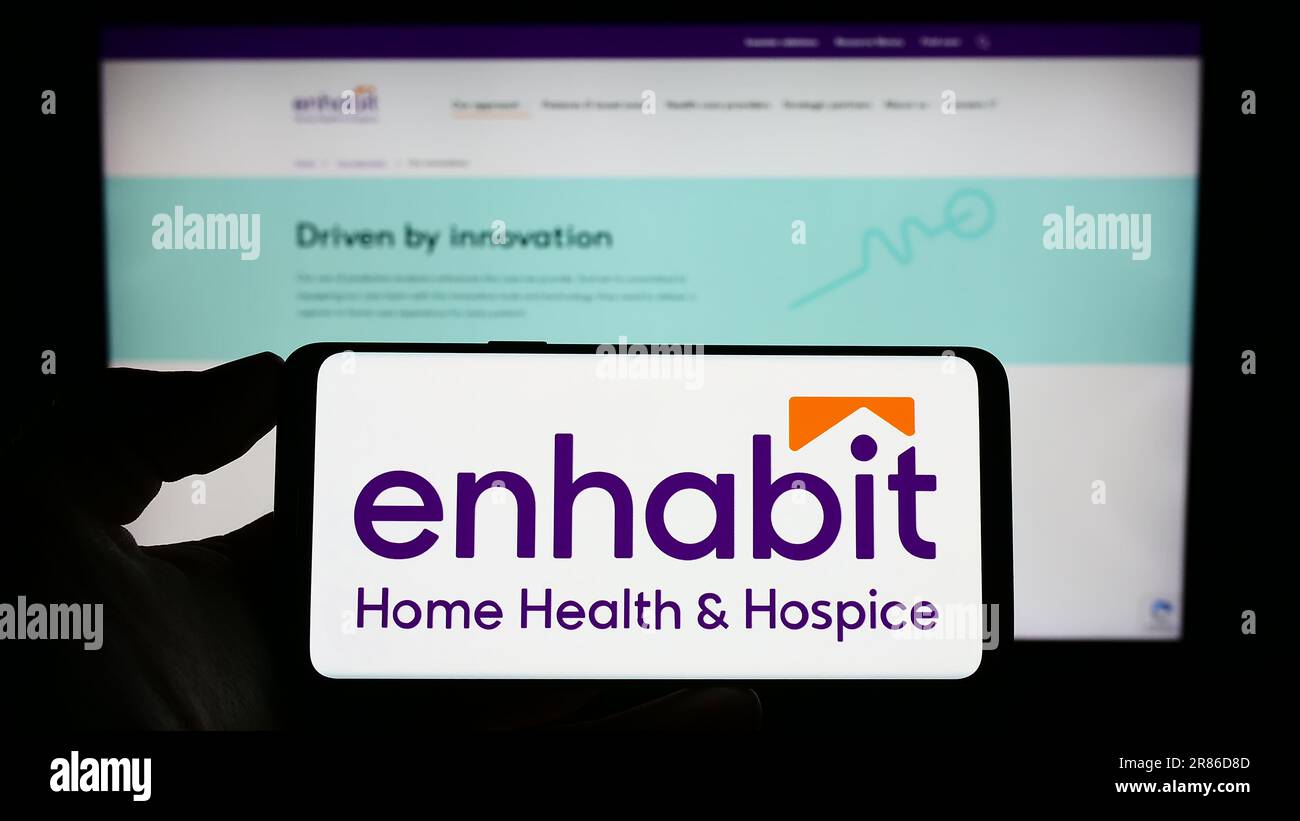 Person holding smartphone with logo of Enhabit Home Health and Hospice ...