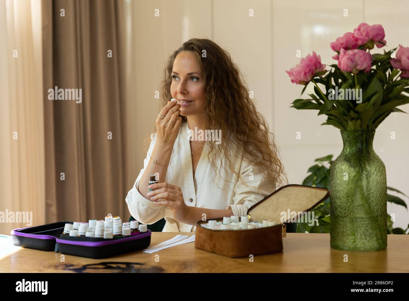 An attractive perfumer girl sniffs a jar of aroma oil and chooses a ...
