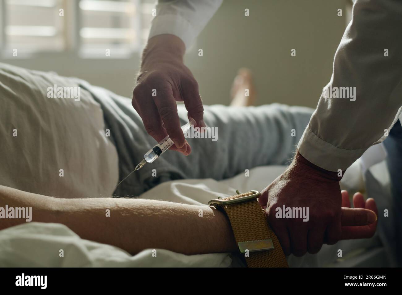 Close-up of doctor of lunatic asylum making injection to young male ...