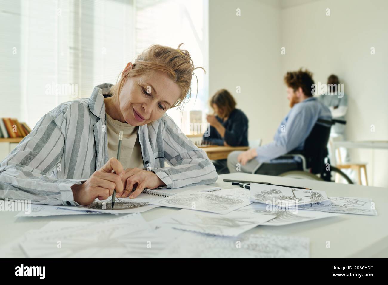 Mature woman with mental disorder drawing something with pencil during ...