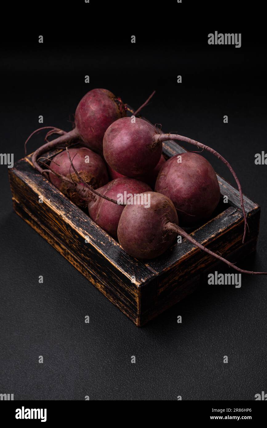Fresh raw beetroot in the form of tubers on a textured concrete background. Vegetarian ...