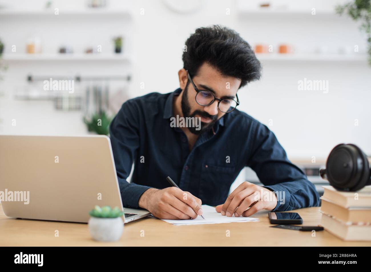 Focus on man's left hand with pen making notes on draft of paper ...