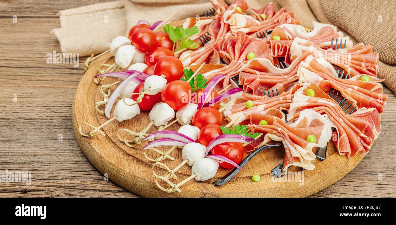 Set of picnic snacks on skewers. Jamon, mozzarella, cherry tomatoes ...