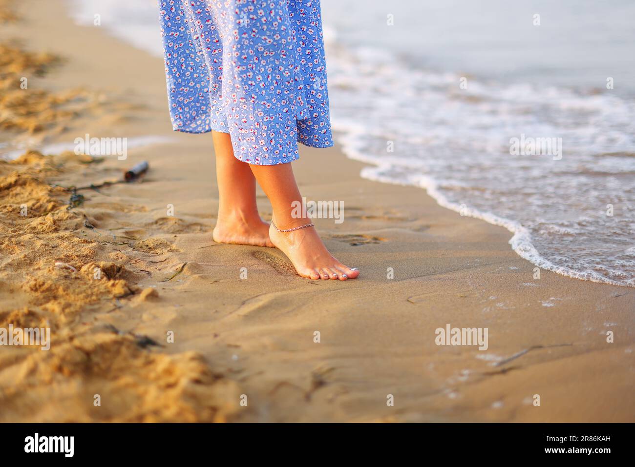 Close up of woman feet walking barefoot on sand beach in sea water ...