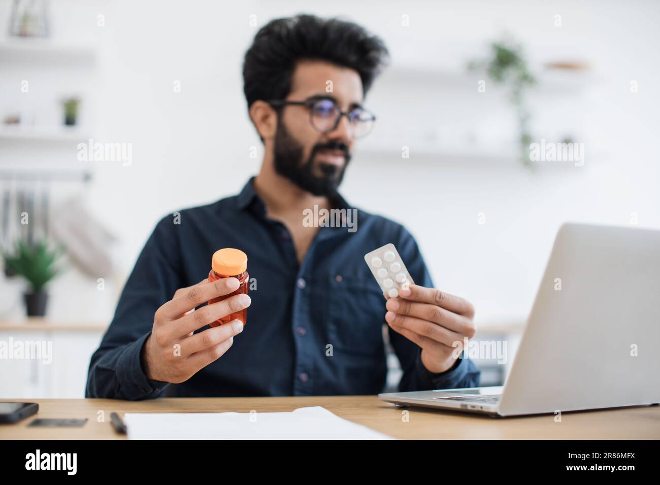 Focus on medicine containers held by arabian young man looking through ...