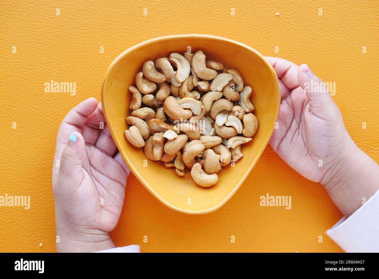 child eating cashew nuts on table Stock Photo - Alamy