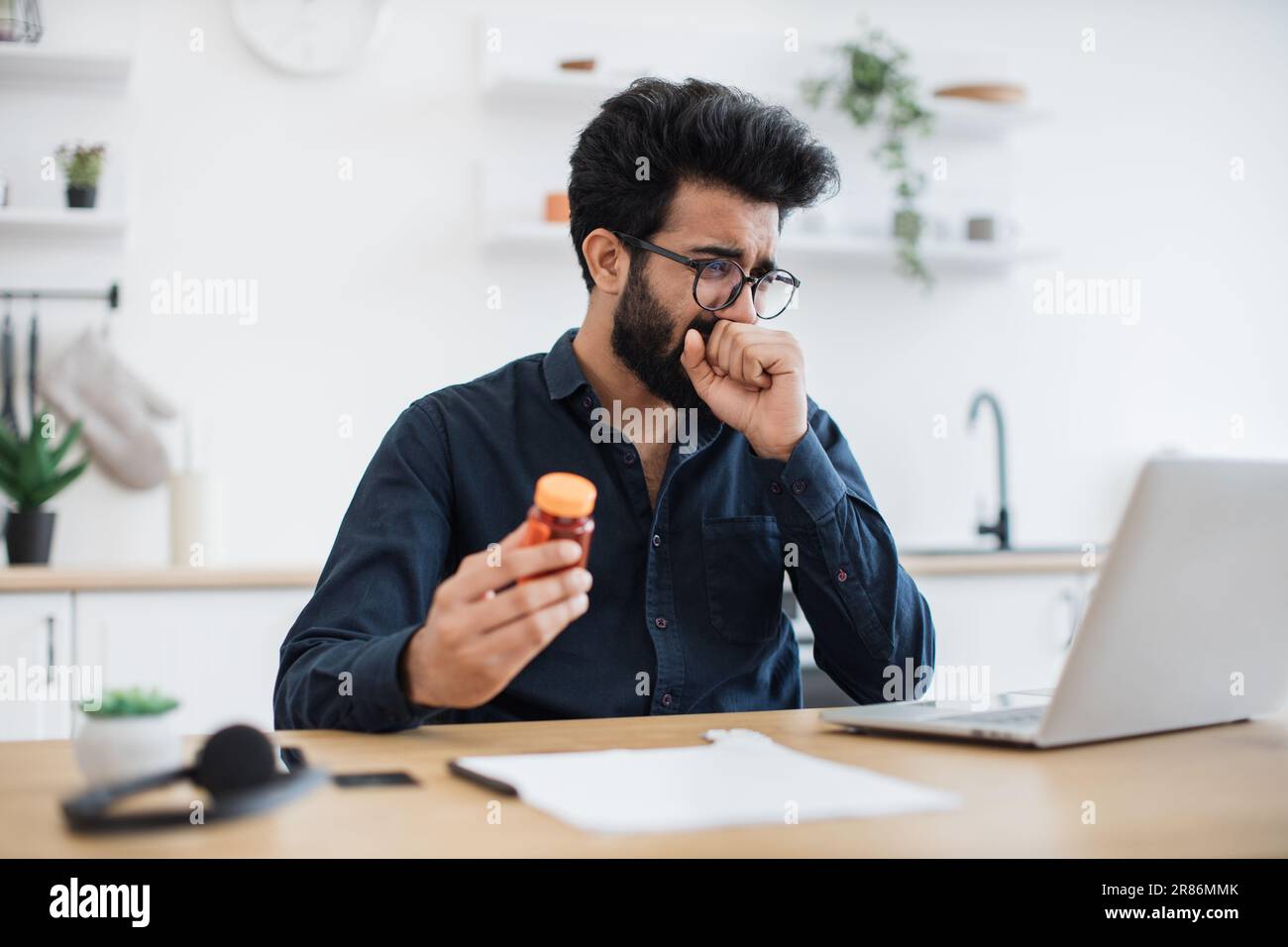 Focus on bottle of pills held by unwell young man having health issues ...
