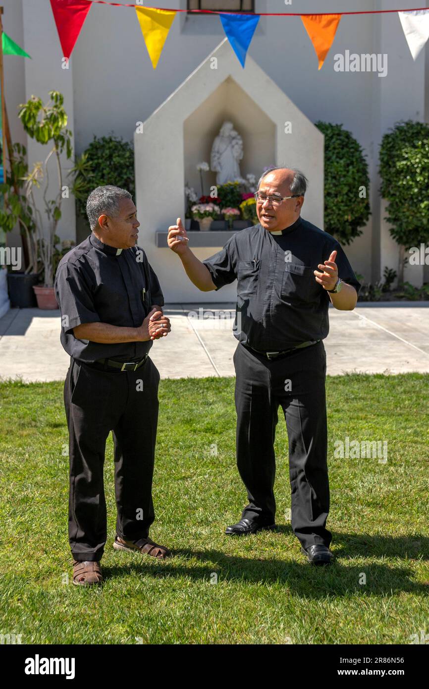 Hispanic and a Vietnamese American priestschat before a shrine to the ...