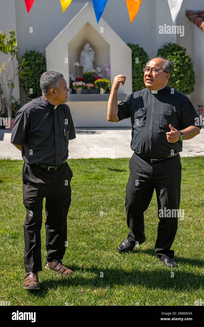 Hispanic and a Vietnamese American priestschat before a shrine to the ...