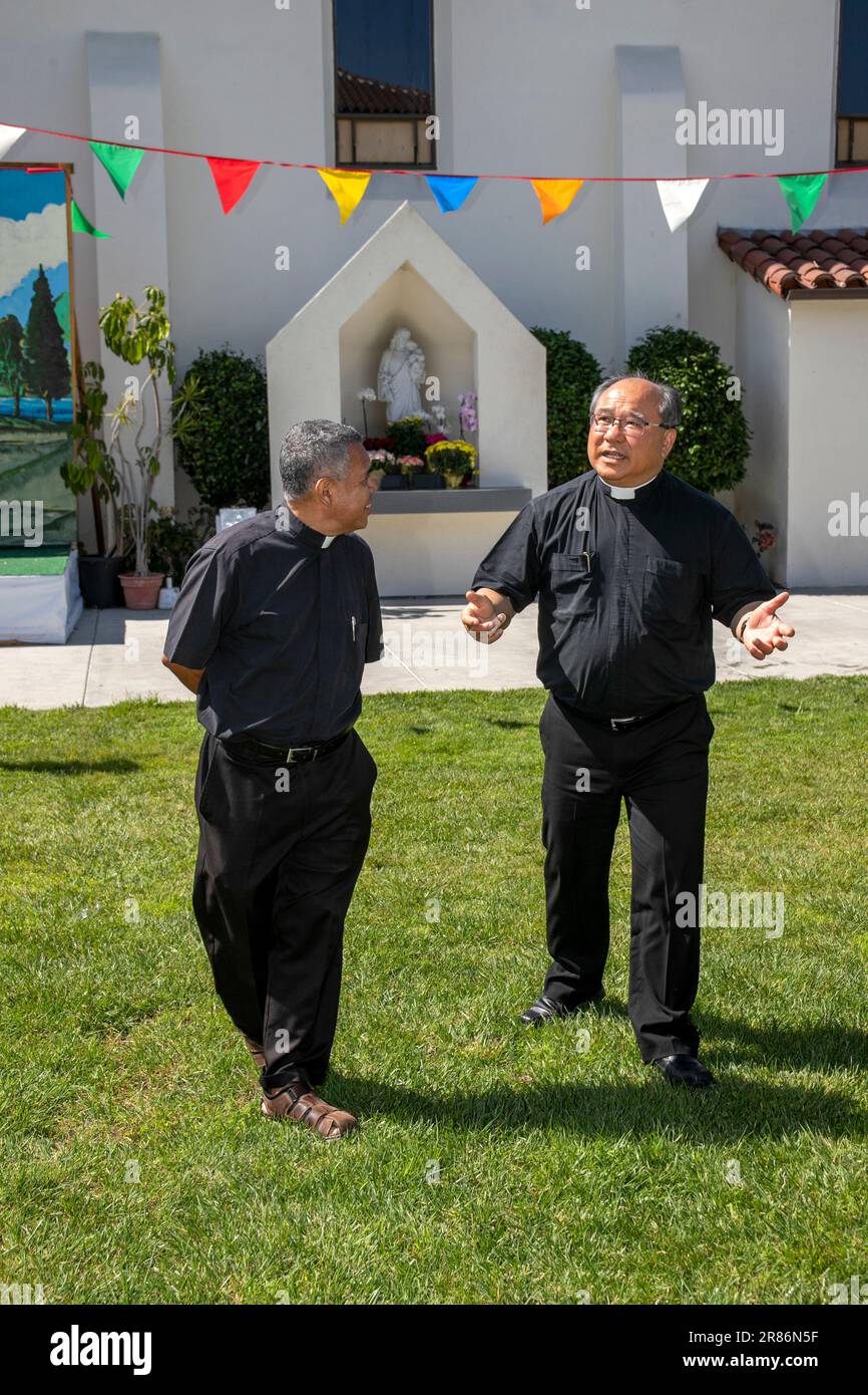 Hispanic and a Vietnamese American priestschat before a shrine to the ...