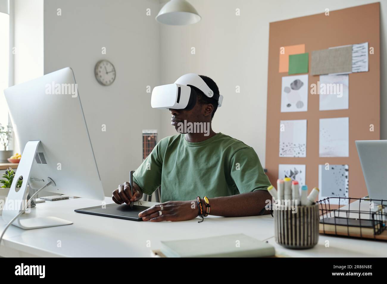 Young graphic designer in extended reality headset using stylus and ...