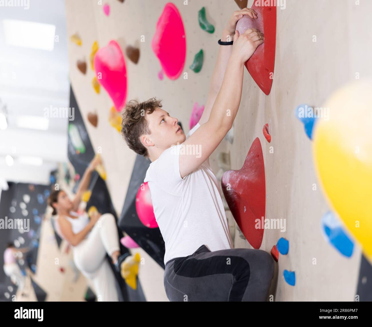 Male mountaineer climbing artificial rock wall without belay indoors ...