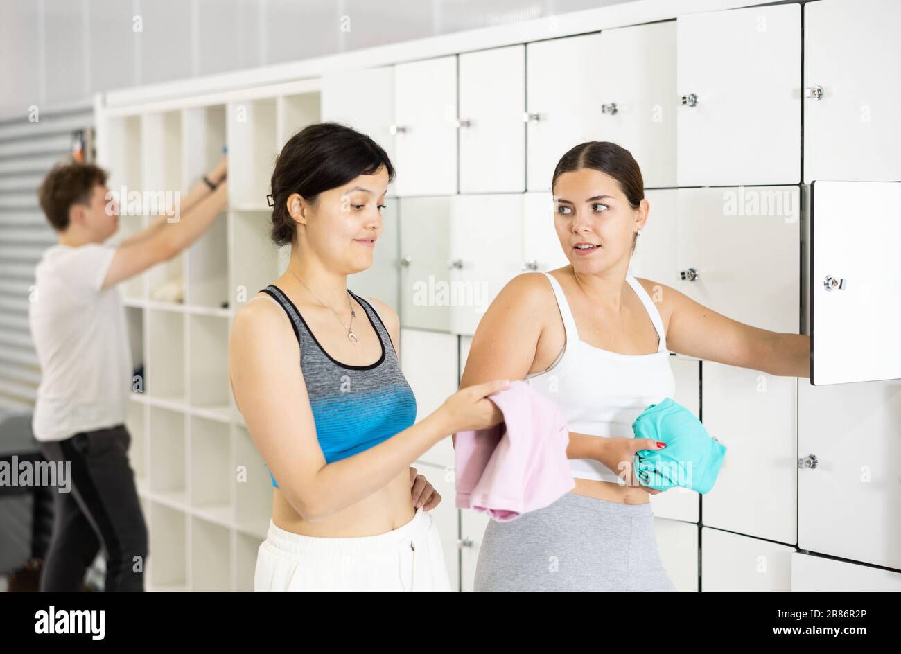 Two young women talking near lockers in locker room Stock Photo - Alamy