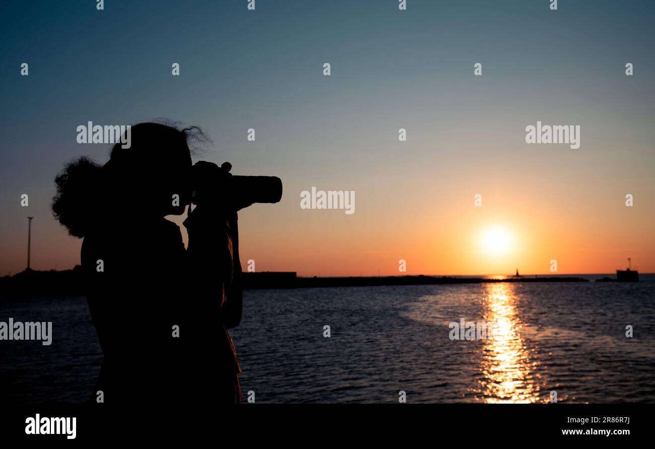 Silhouette of a photographer in action at Malmo harbor during late ...