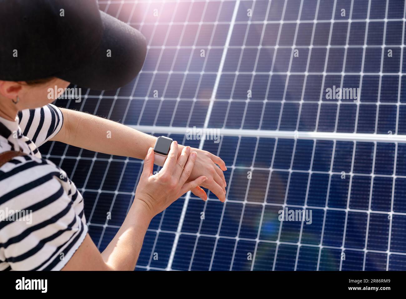 Woman in cap using her smartwatch on her hand on background with solar ...