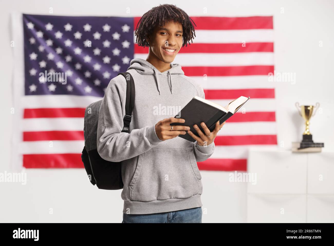Male african american student standing and reading a book in front of a ...