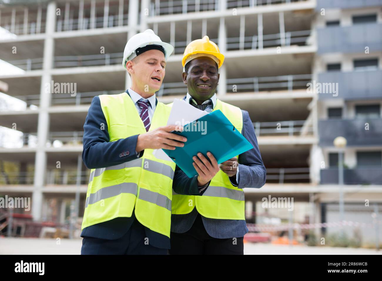 Builders talking about work outdoors Stock Photo - Alamy