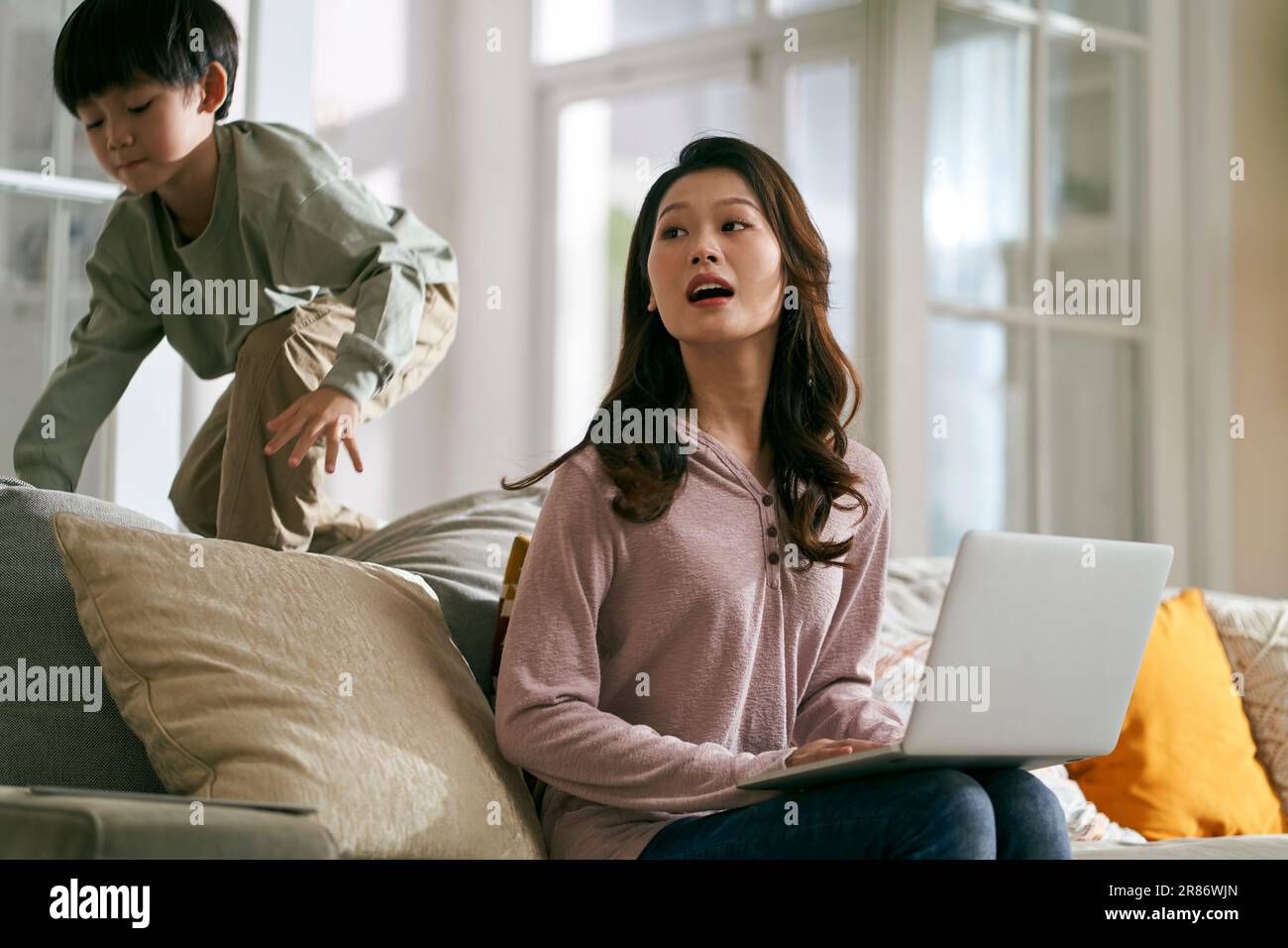 young asian businesswoman mother trying to work at home annoyed by ...