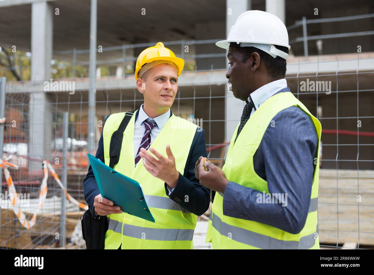 Two civil engineers are discussing the construction plan, holding ...