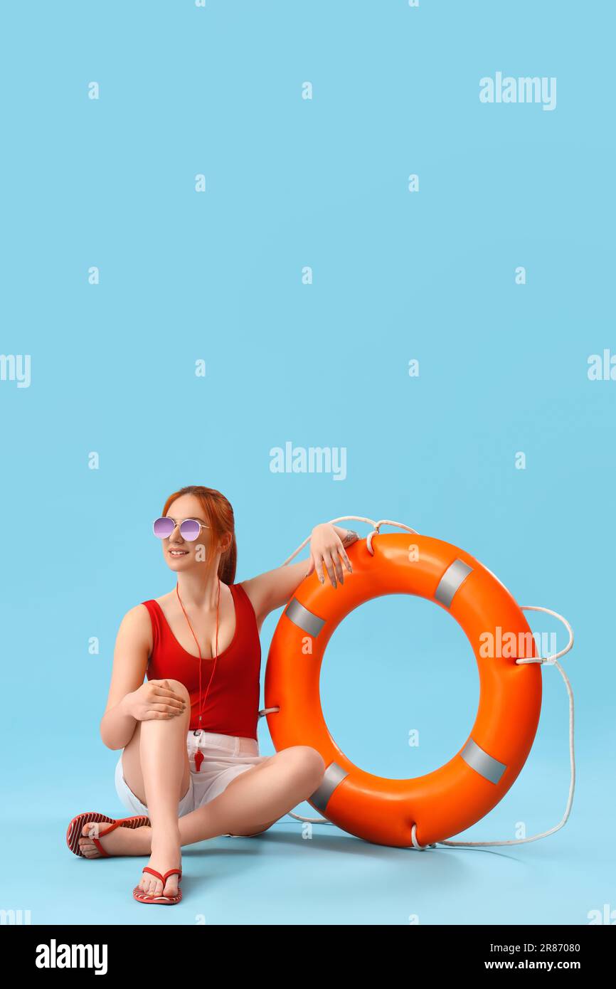 Female lifeguard with ring buoy sitting on blue background Stock Photo ...