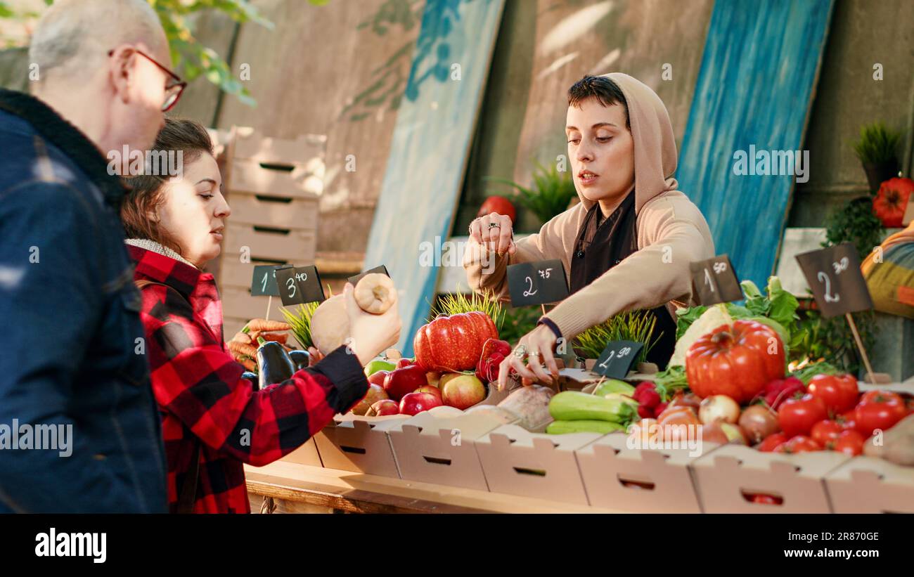 Female local farmer talking to customers about homegrown produce ...