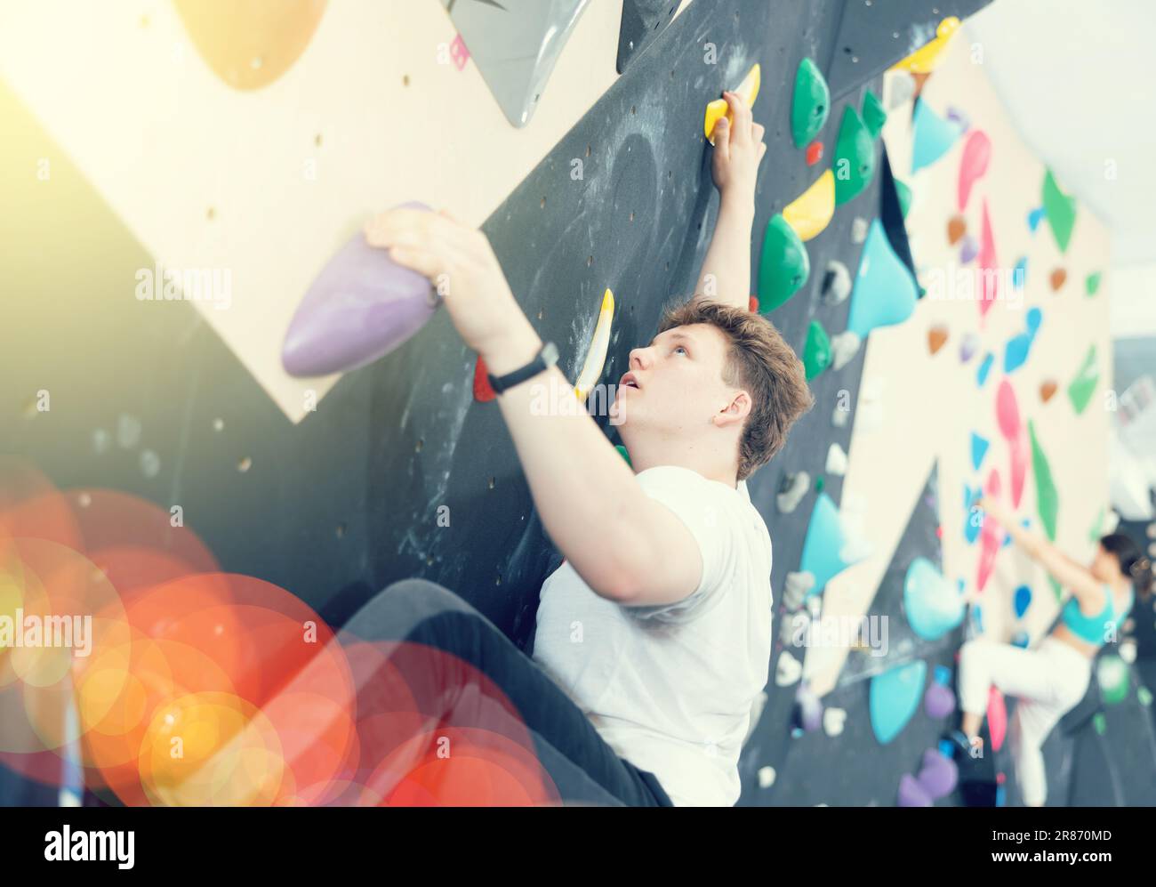 Male mountaineer climbing artificial rock wall without belay indoors ...