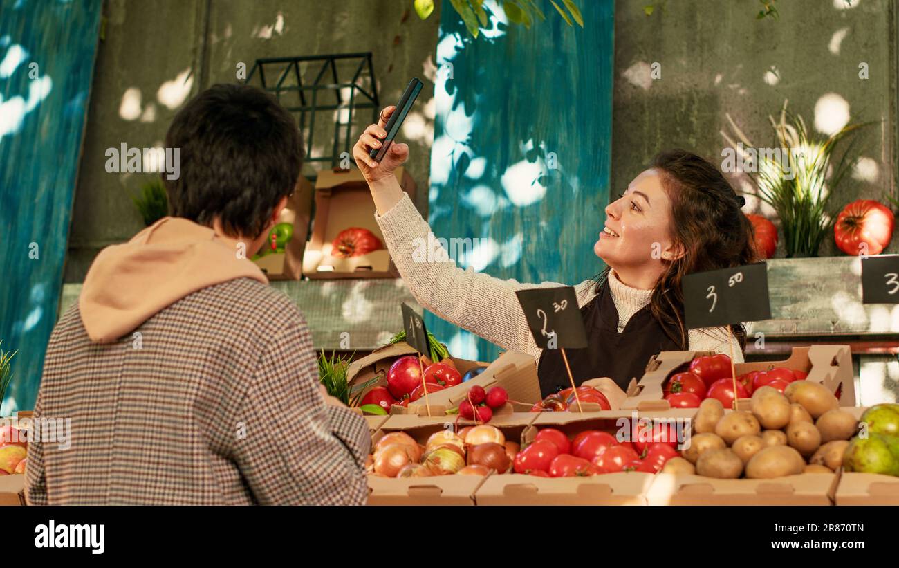 Young farmer recording video on smartphone with regular client ...