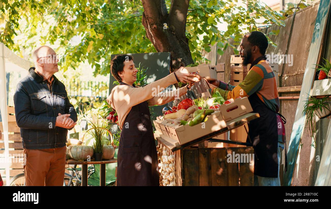 Team of diverse vendors giving box filled with organic fruits and ...