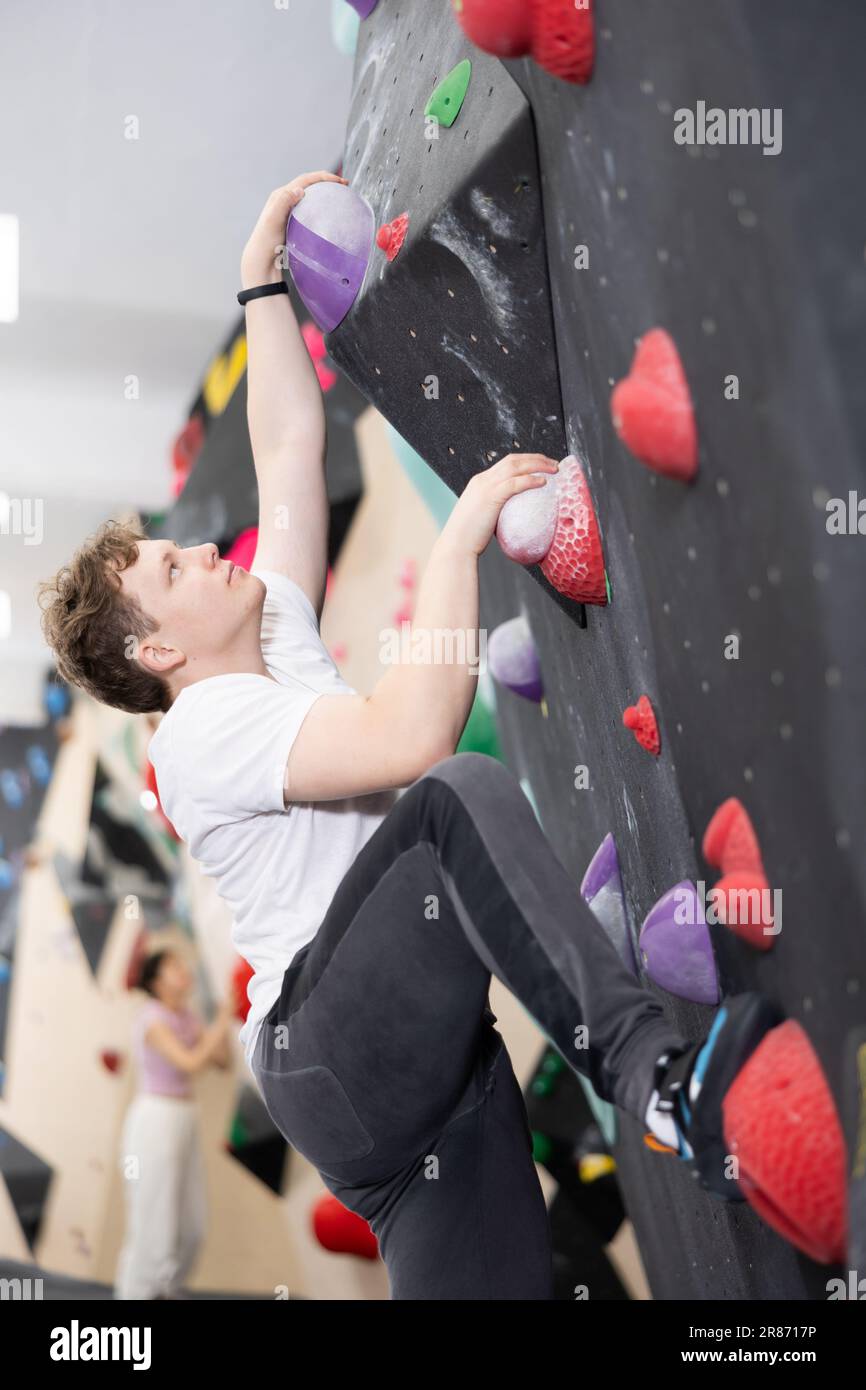 Teenage boy climbs steep artificial wall in sports complex and trains ...
