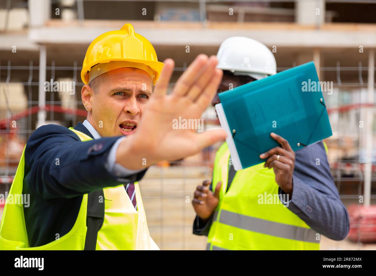 Young engineer shows a stop sign with his hand about the termination of ...