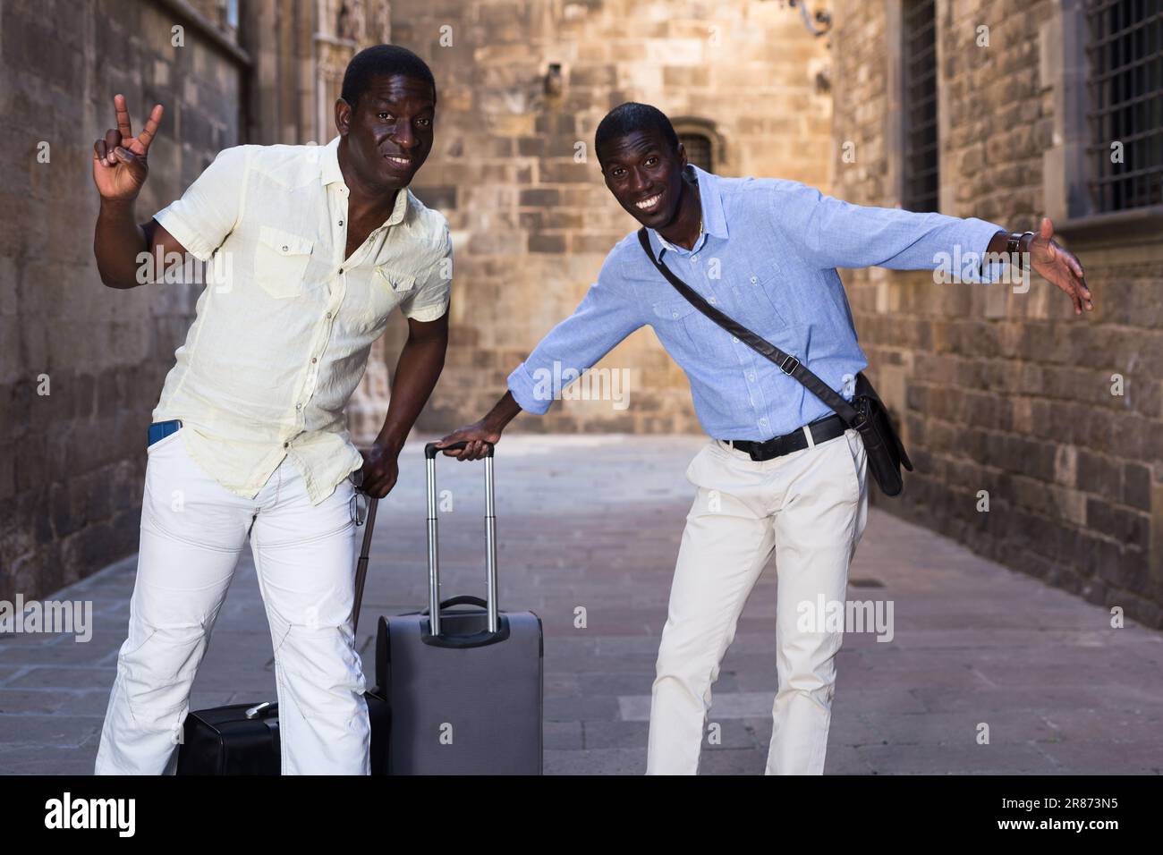 Portrait of smiling happy friends tourists with luggage on the street ...