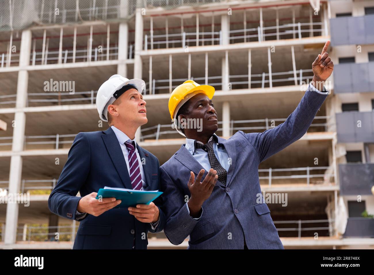Engineers in suits and hardhats discussing on building site Stock Photo ...