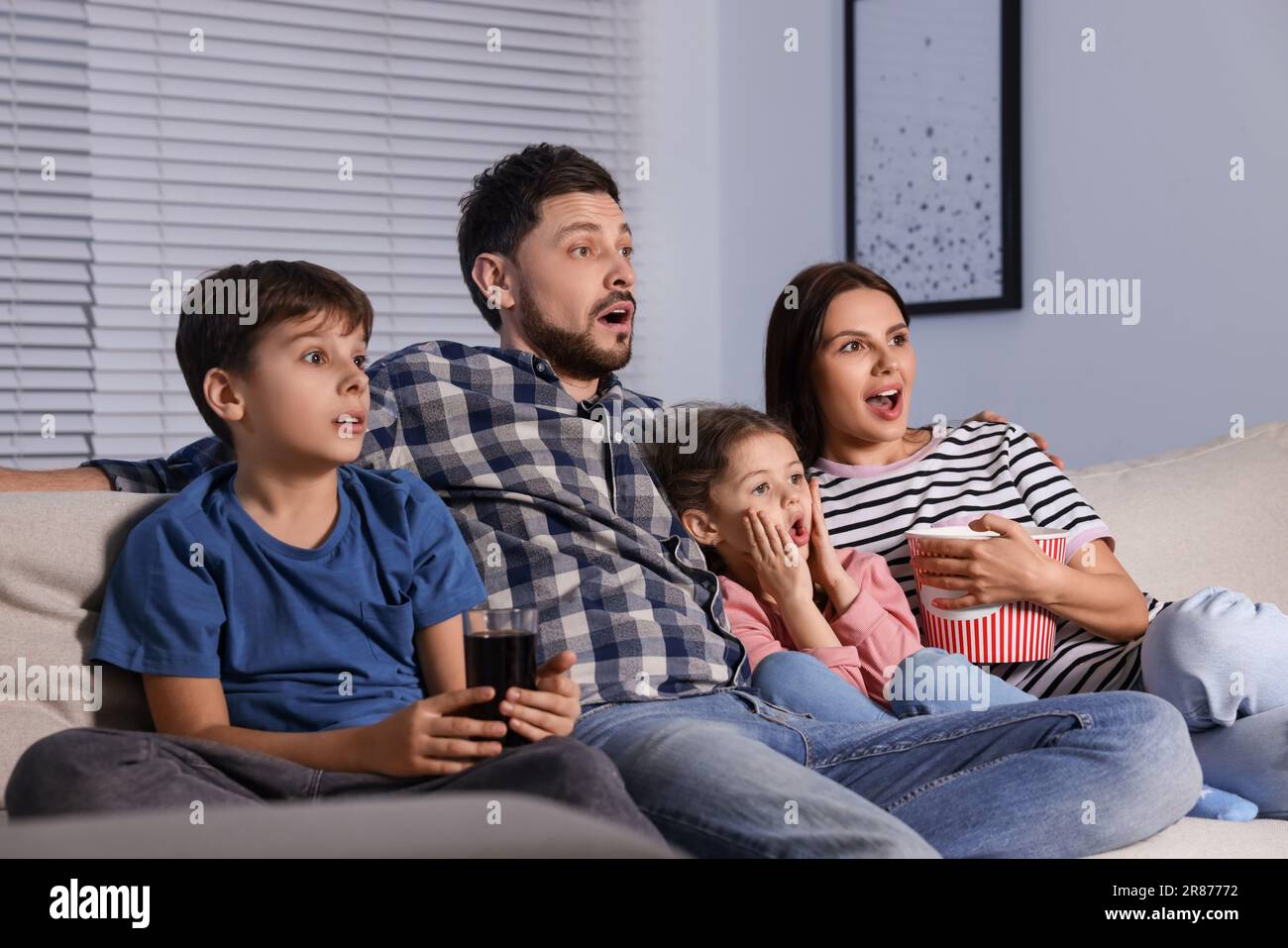 Shocked family watching TV at home in evening Stock Photo - Alamy